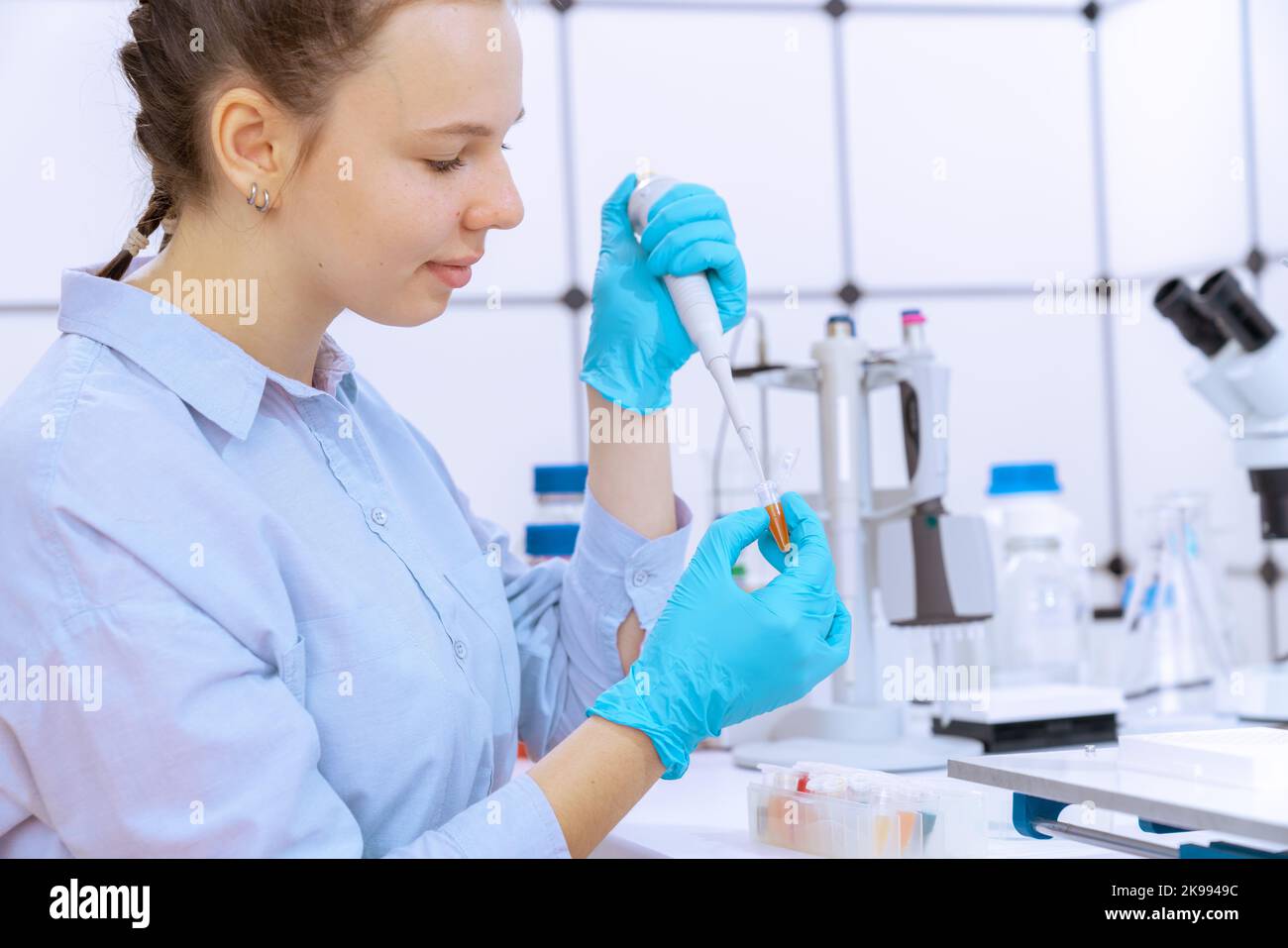young female student loads biological samples into microtube strips for PCR analysis. University ...