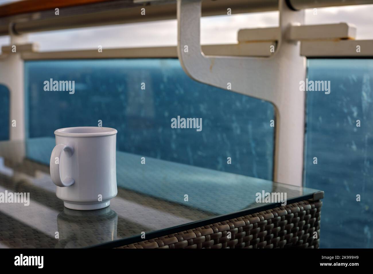 cup of tea resting on the table of a cruise ship with the ocean at the ...