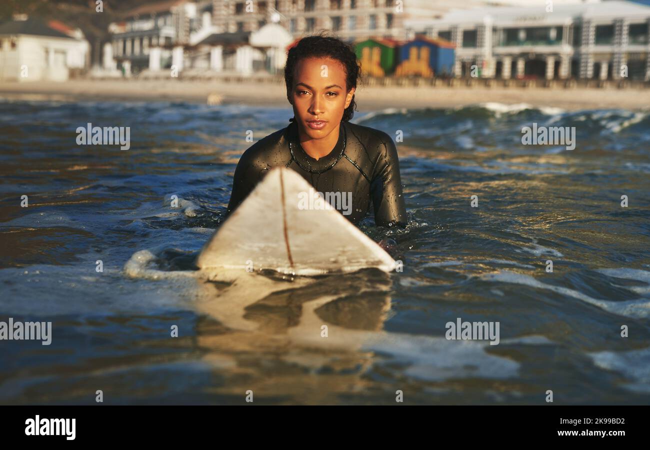 Shes serious about surfing. Portrait of a beautiful young woman surfing ...