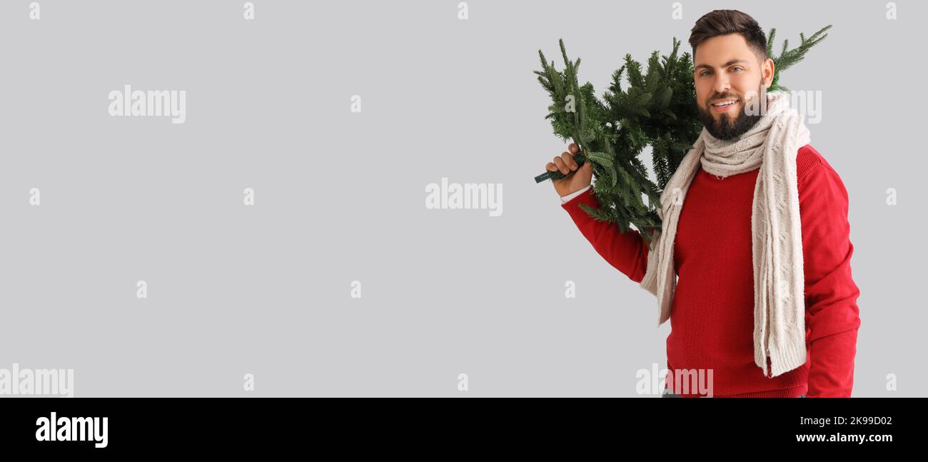 Handsome man holding Christmas tree on light background with space for ...