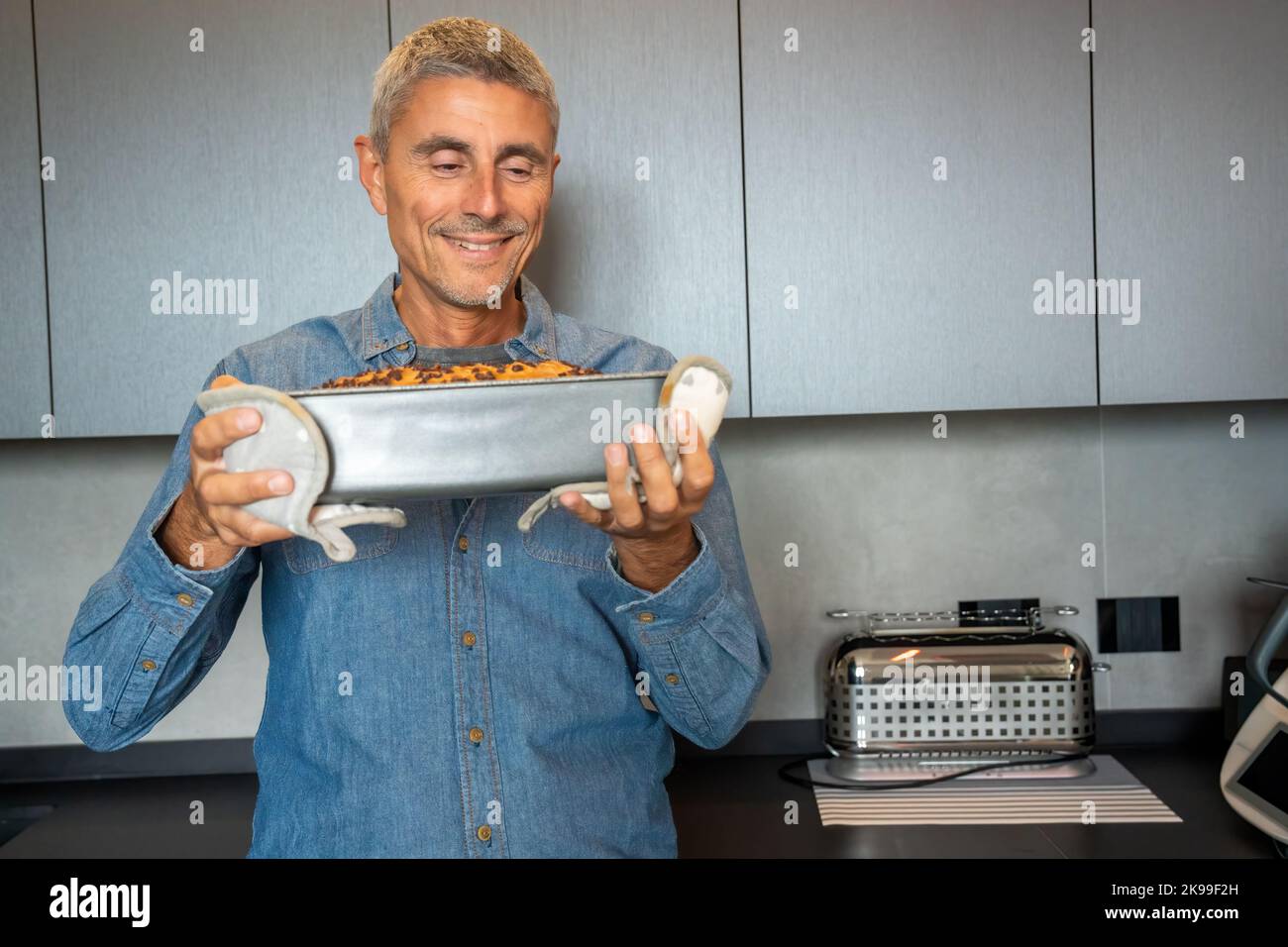 Happy man holding a board with a tasteful cake and sniffing the ...