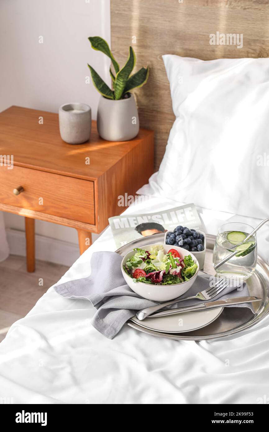Tray with vegetable salad, blueberries and glass of cucumber water on ...