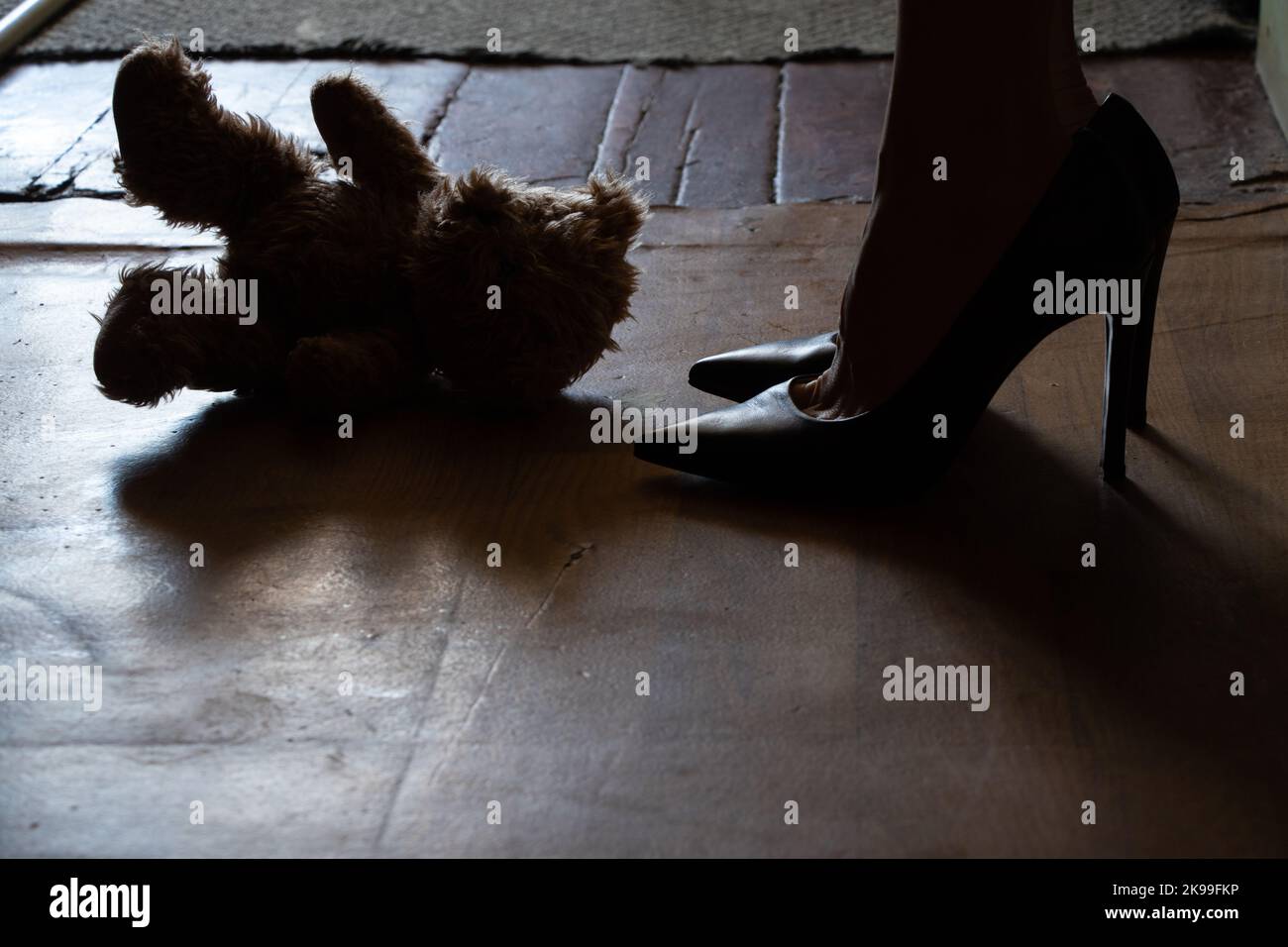 female feet next to a baby teddy bear on the floor in the dark in the ...
