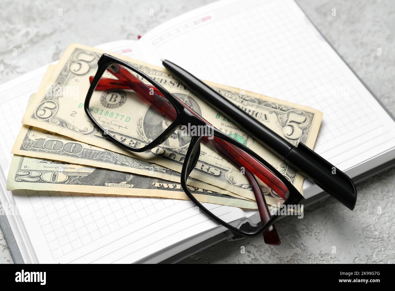 Notebook with eyeglasses, pen and dollar banknotes on grunge background ...