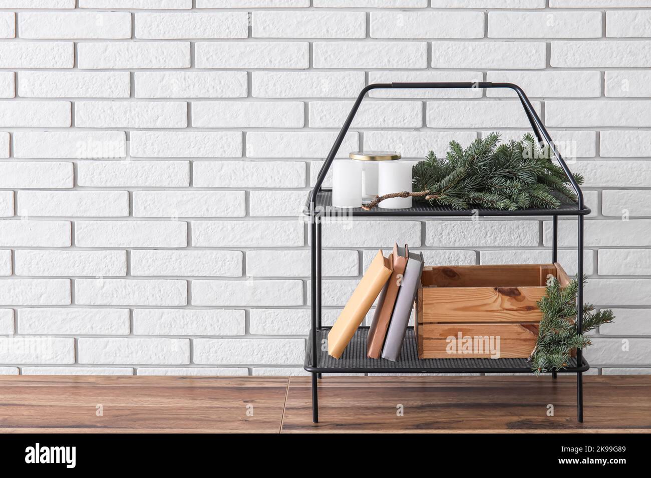 Shelving unit with Christmas branches, candles and books near white ...