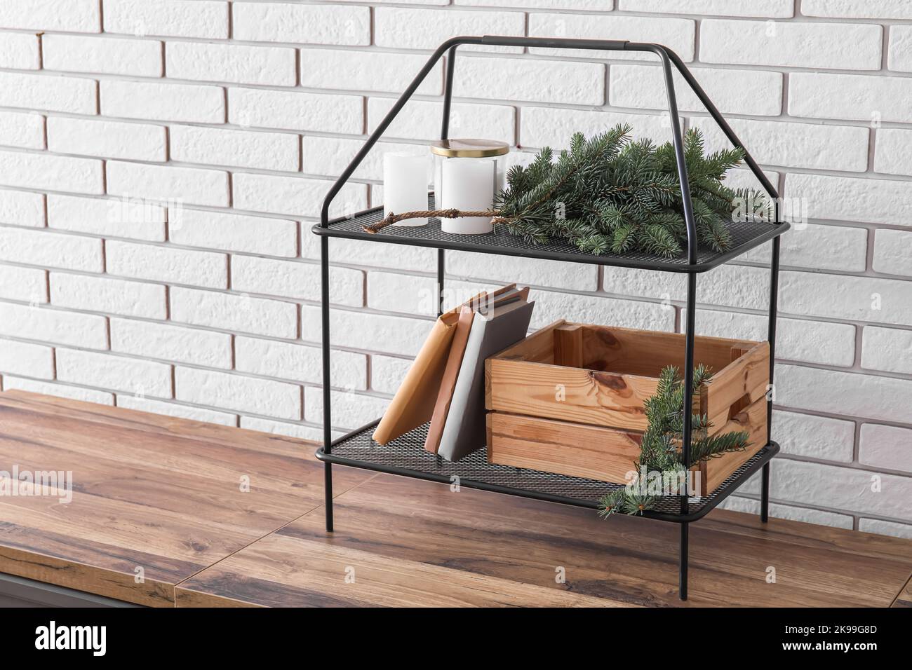 Shelving unit with Christmas branches, candles and books near white ...