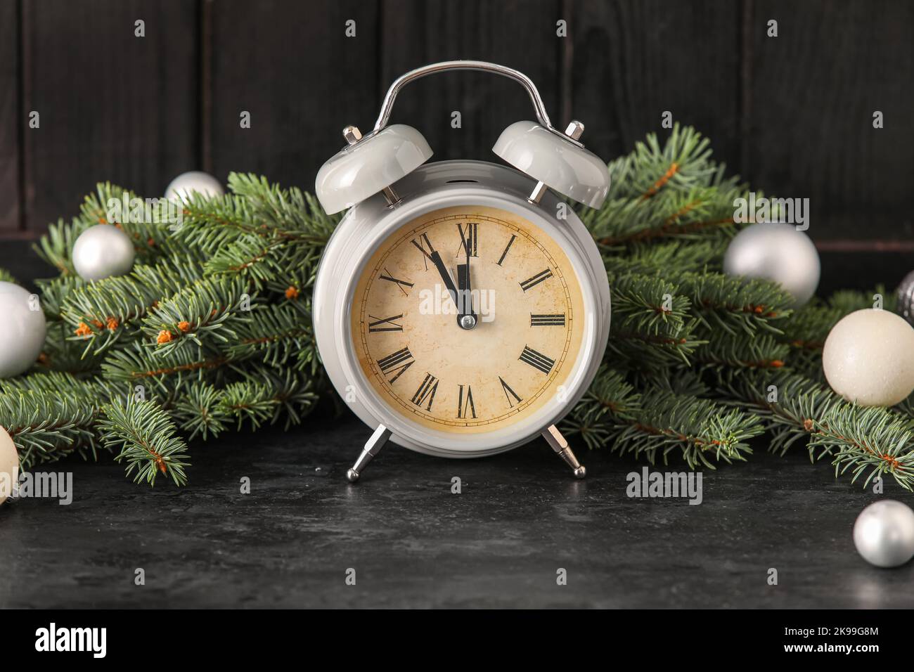 Alarm clock with Christmas balls and fir branches on dark wooden ...