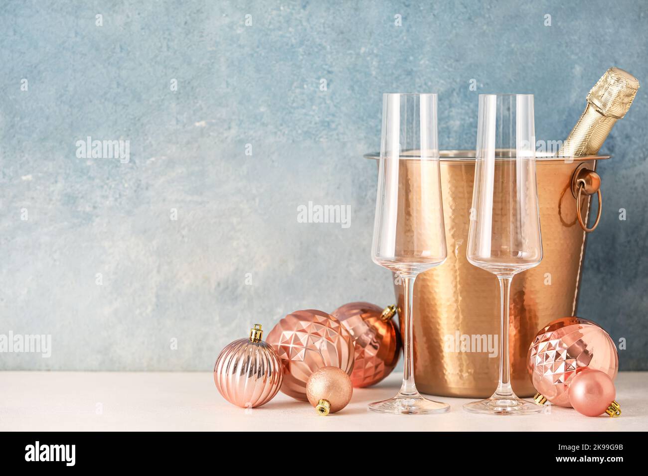 Bucket with bottle of champagne, glasses and Christmas balls on table ...