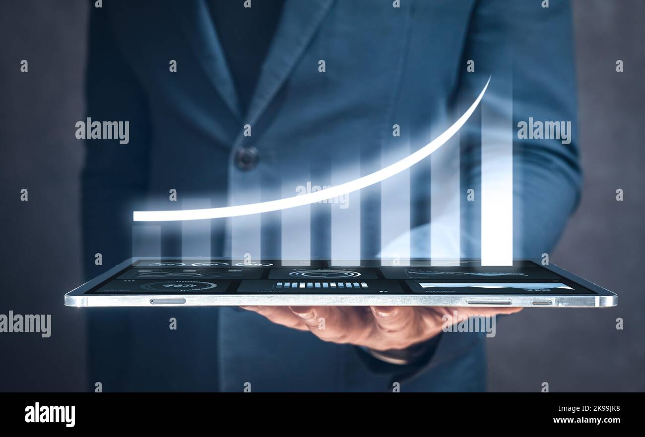 Businessman holding tablet analyzing sales data and economic growth ...