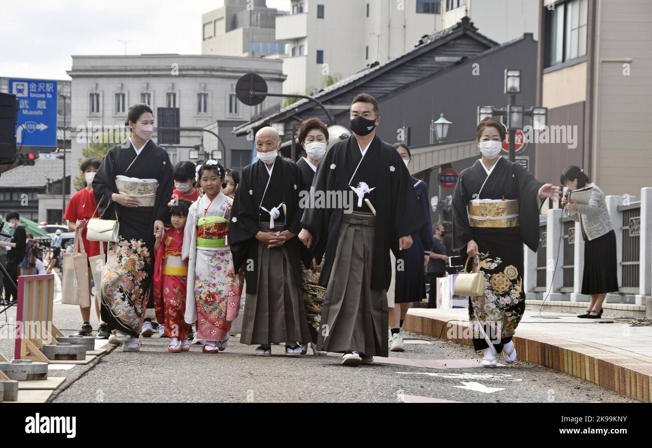 Local residents in traditional Japanese clothes walk across Asanogawa ...