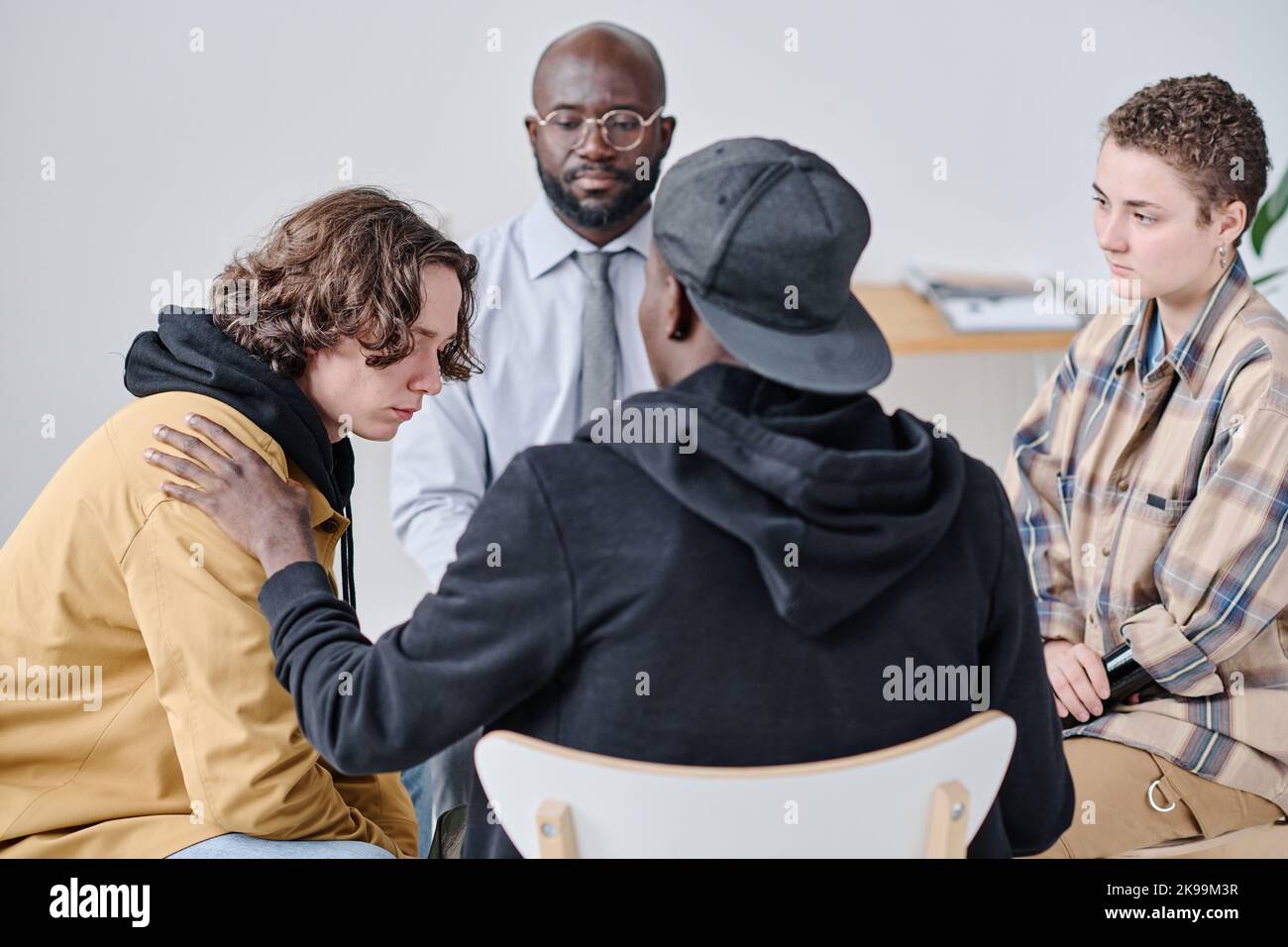 Teenage boy talking about problems to other people while they ...