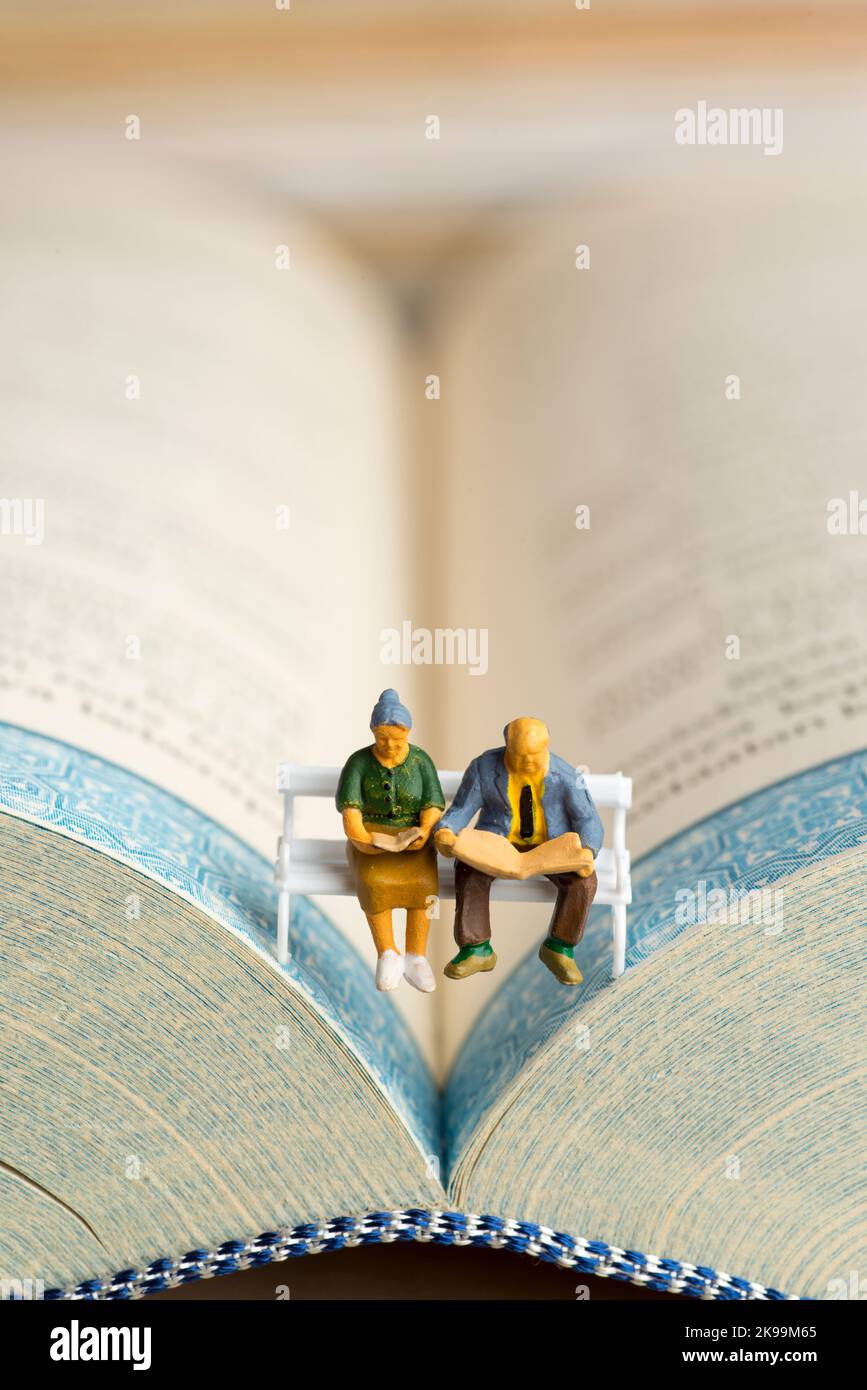 Close up of miniature figures of an elderly couple read book and ...
