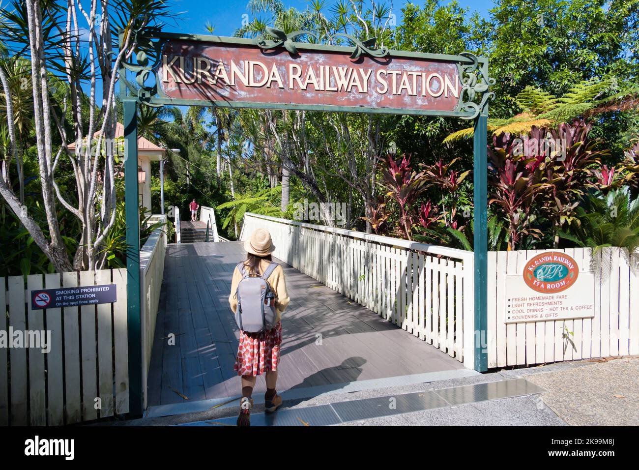 A lday is walking through the gate of Kuranda raiway station ...