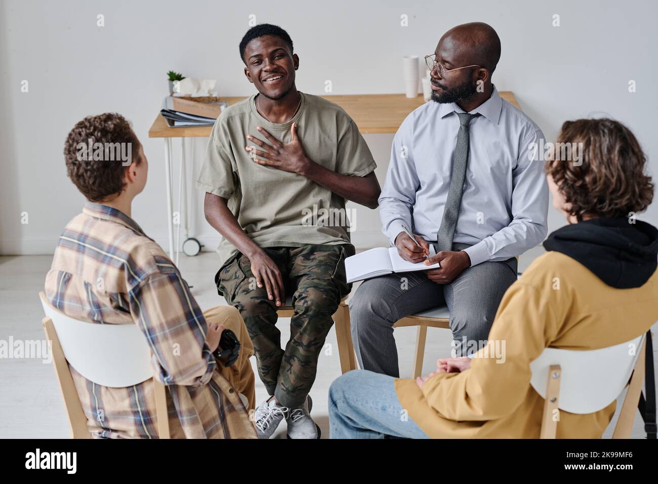 African happy young guy talking to people and smiling while visiting ...