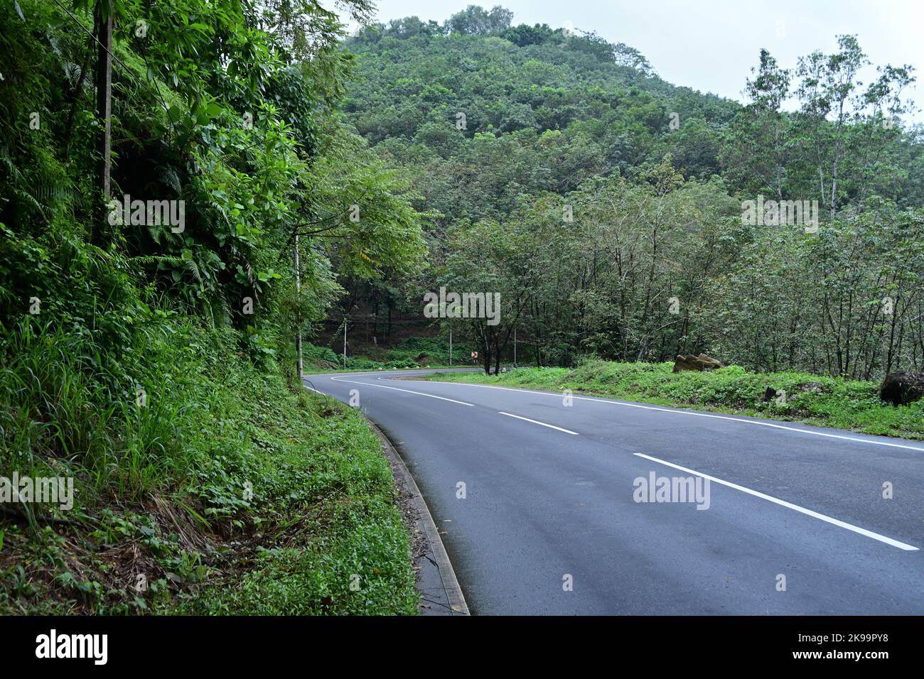 Roadside view of a steep mountain road on rainy day with sharp turn ...