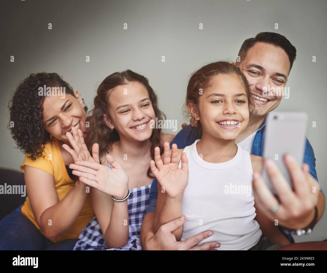Say hi to granny. a family of four video calling using a cellphone ...