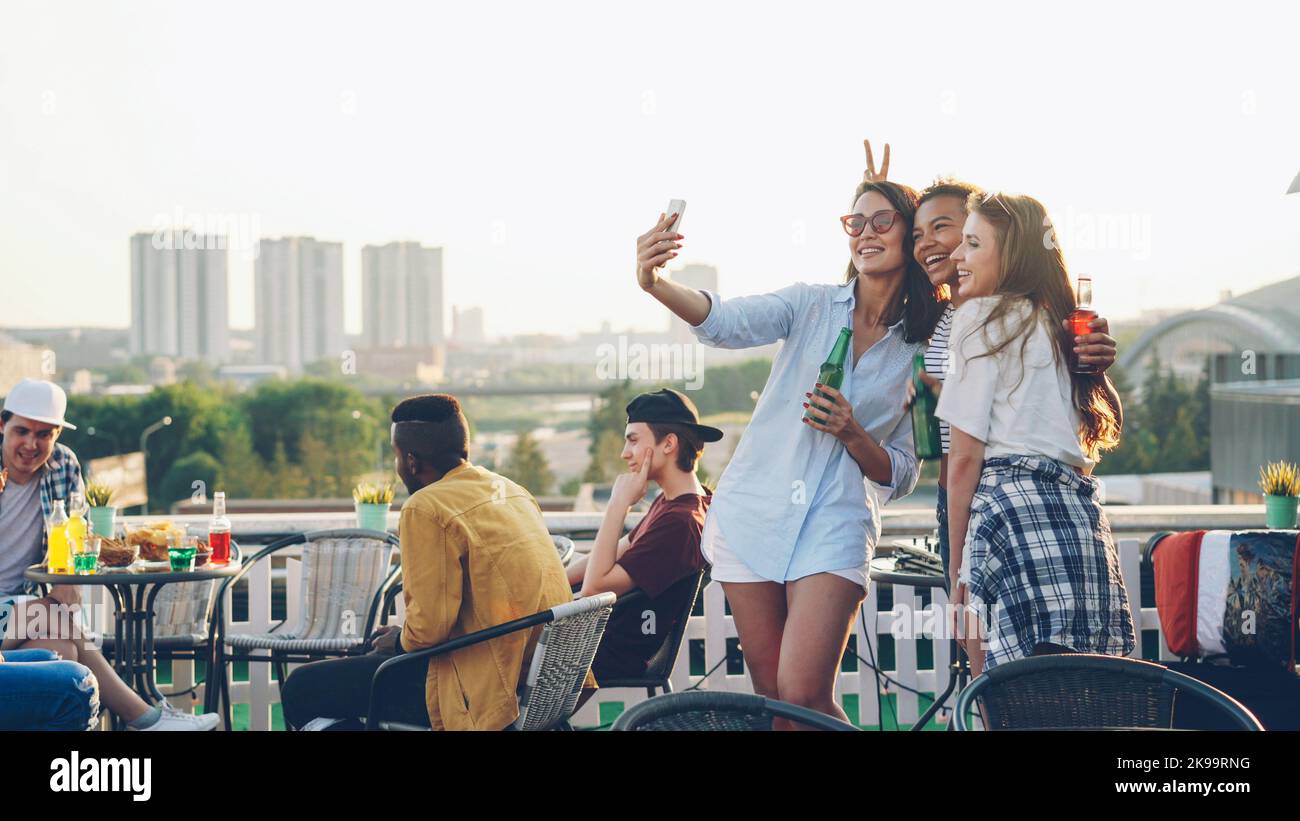 Playful young women are taking selfie with smartphone making funny ...
