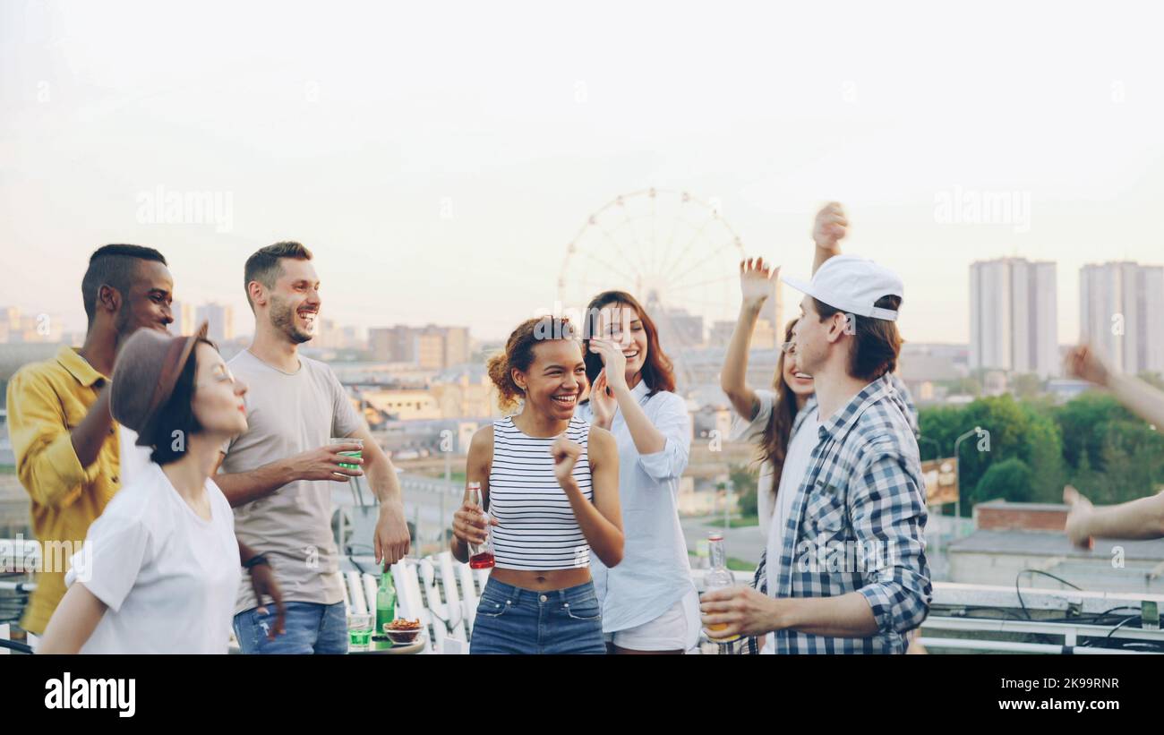 Happy friends are dancing at rooftop party while professional DJ is ...