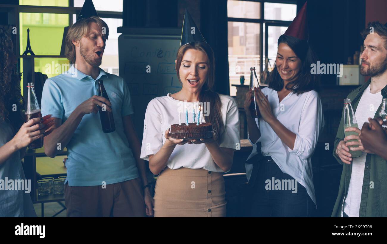 Company employees are celebrating birthday, woman is holding cake ...
