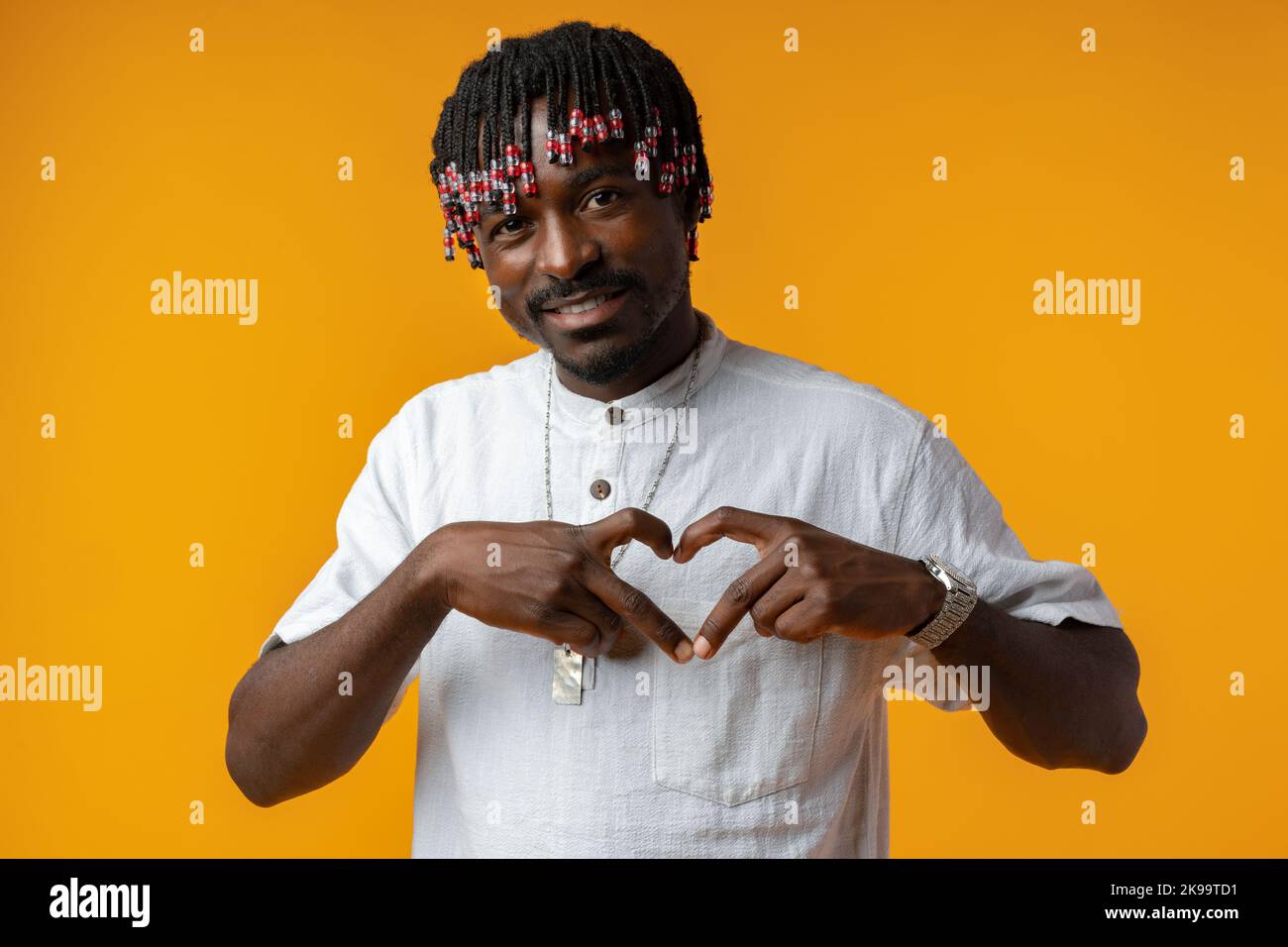 African man showing heart shape with hands on yellow background Stock ...