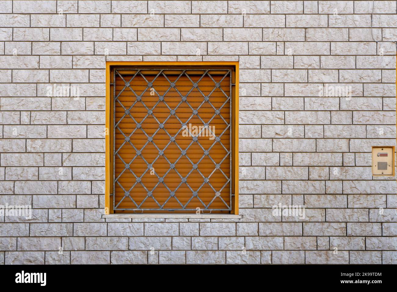 A modern facade covered with white stone brick and windows protected ...