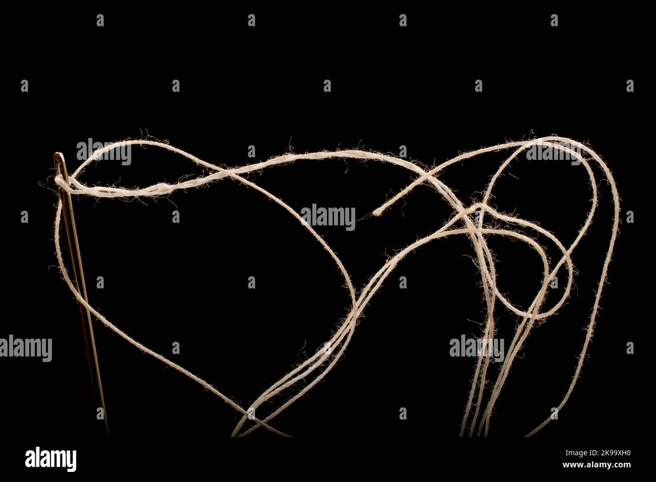 Needle and white cotton, tangled yarn on roll for sewing. Thread used ...