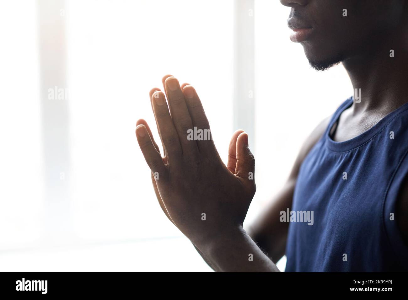 Close-up of African young man folding his hands and concentrating on ...