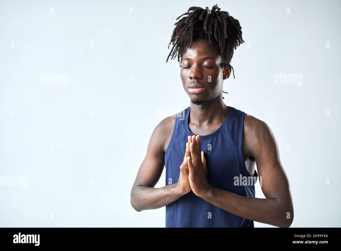 Portrait of African young man meditating with his eyes closed standing ...
