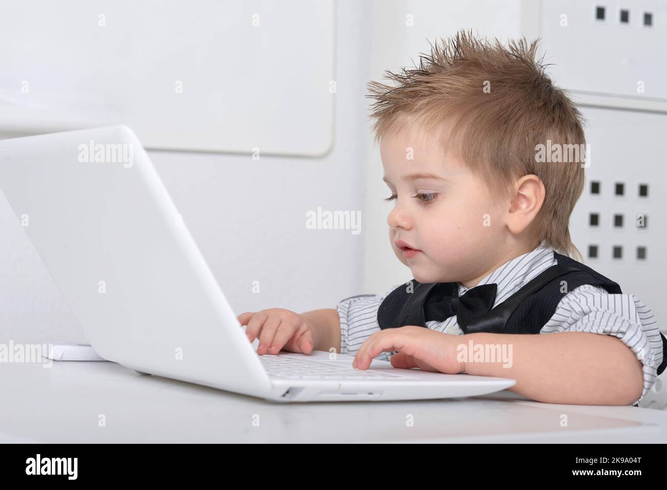 Little handsome boy sits with a computer Stock Photo - Alamy