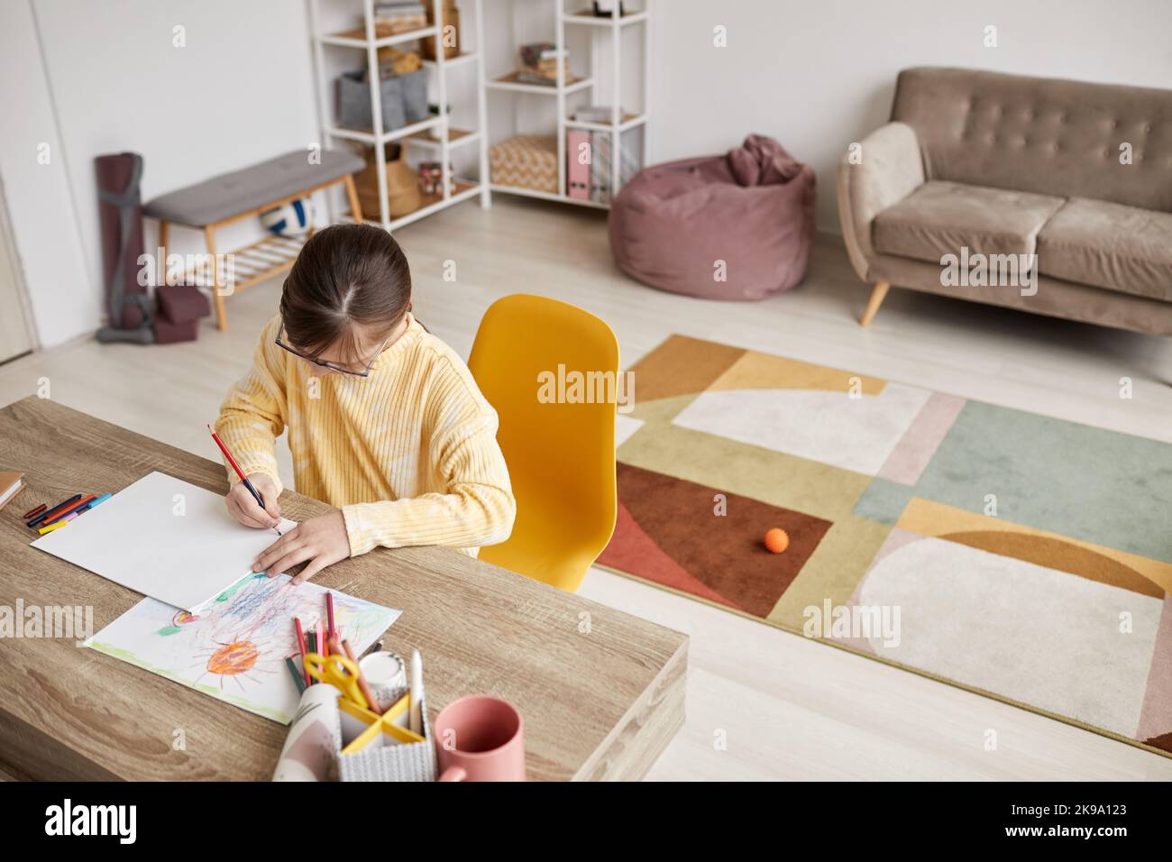 Minimal high angle portrait of teenage girl drawing pictures at table ...