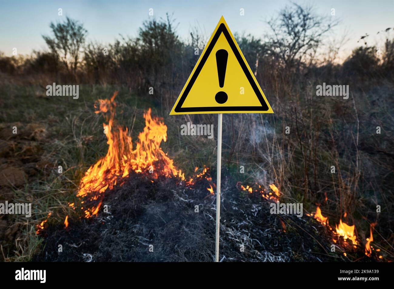 Burning dry grass and warning sign with exclamation mark warns about ...