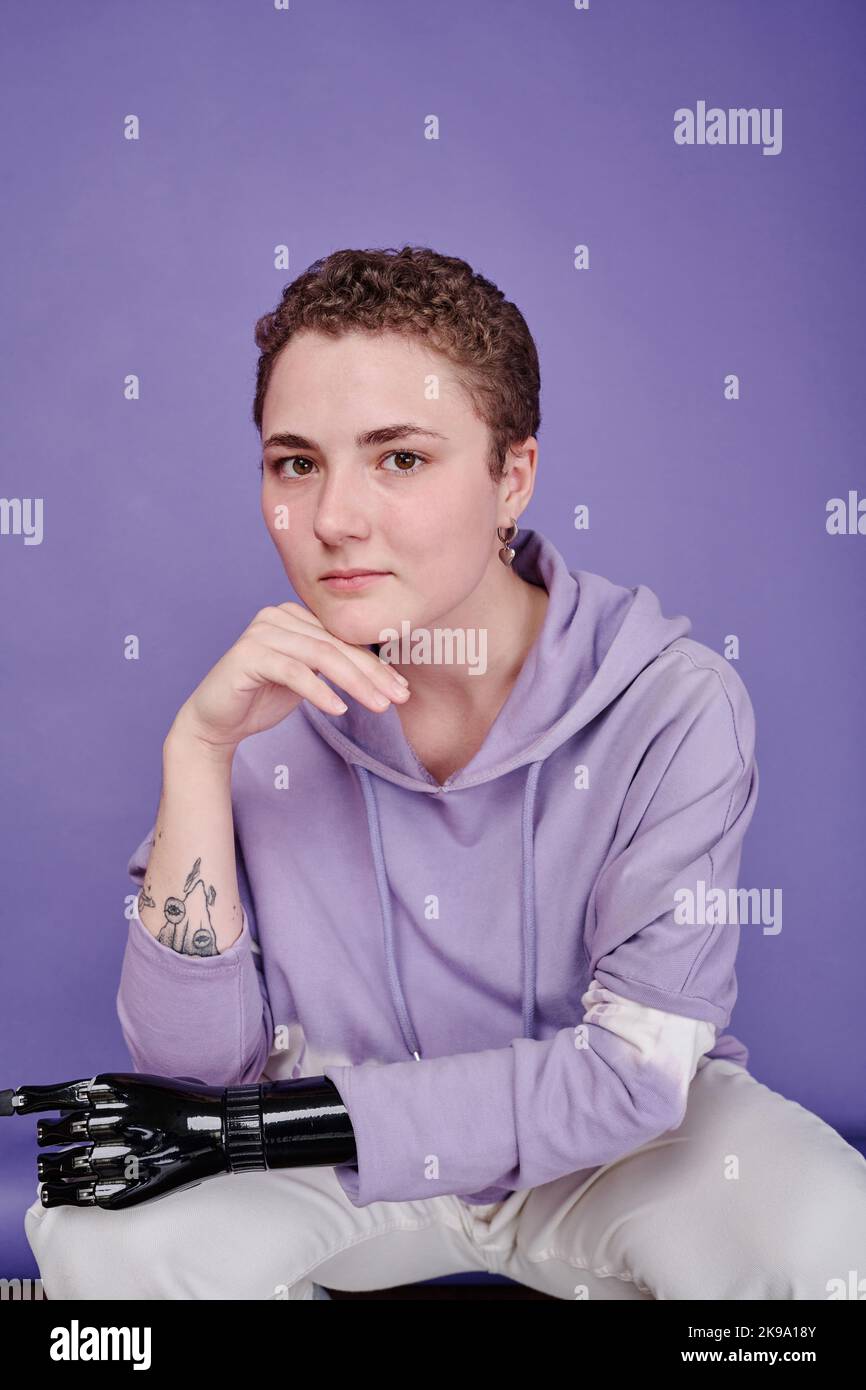 Portrait of young woman with prosthetic arm looking at camera against ...