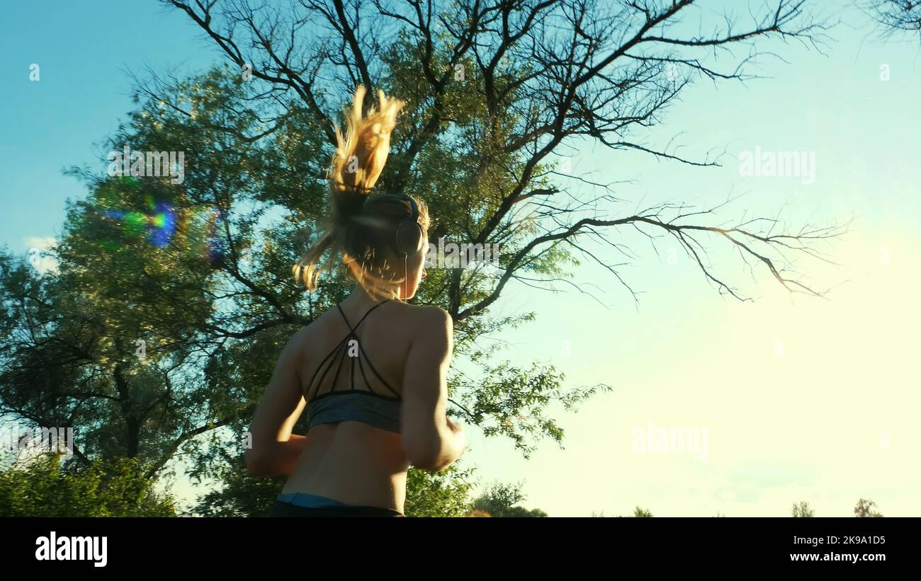 Beautiful, high, athletic blonde young woman, girl puts headphones and ...