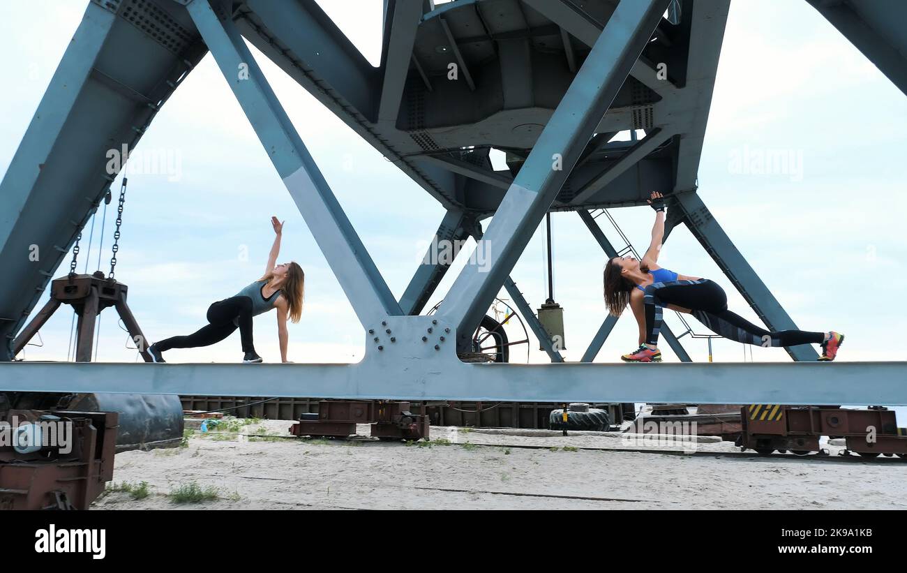 Two young, athletic women, perform strength exercises.They stand on the ...