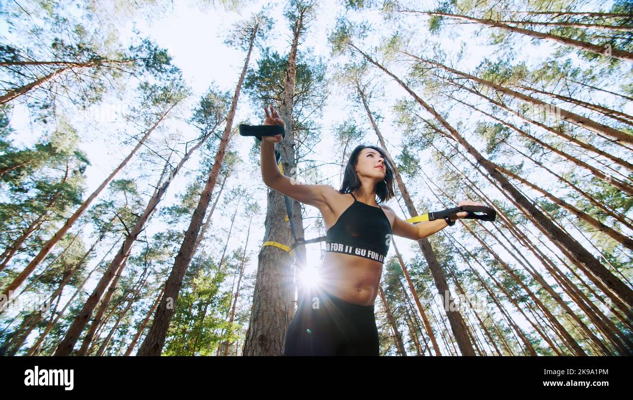 athletic woman, coach, instructor, performs, doing exercises. In pine ...