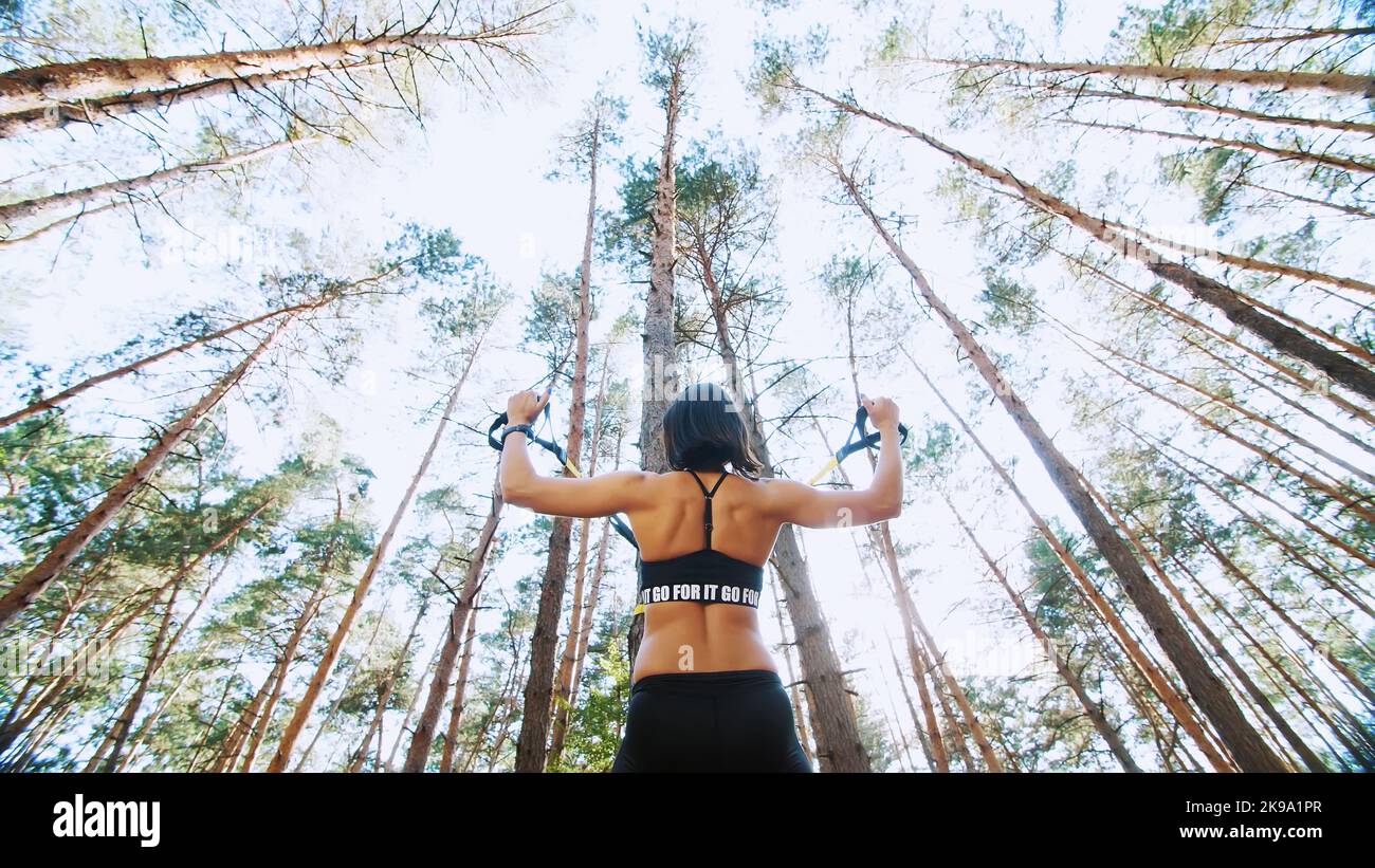 athletic woman, coach, instructor, performs, doing exercises. In pine ...
