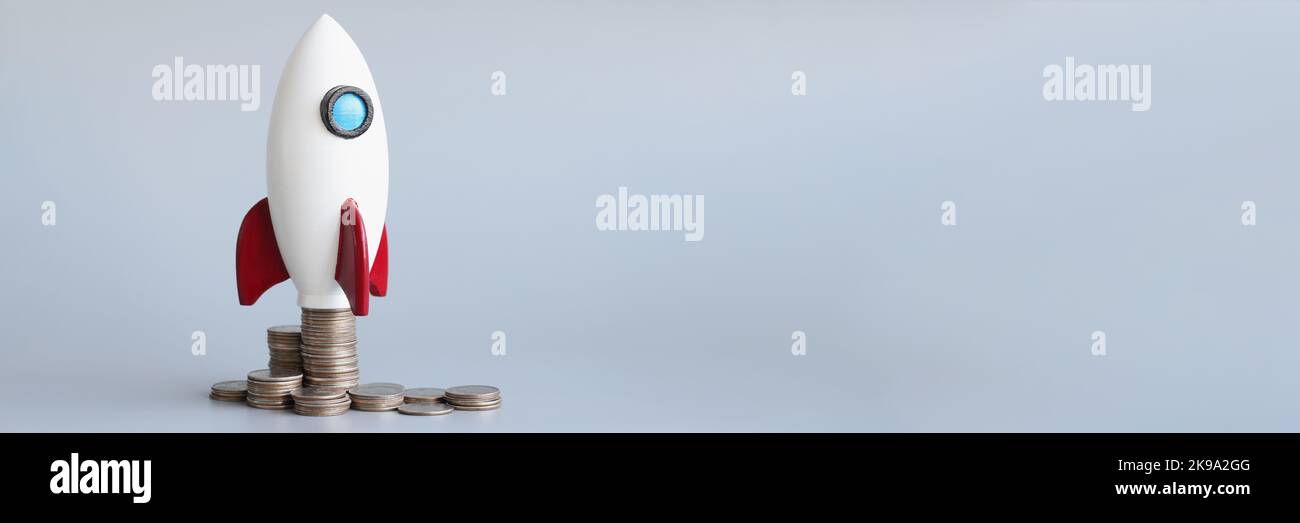Miniature rocket stand on stack of coins, rocketship as symbol to open ...