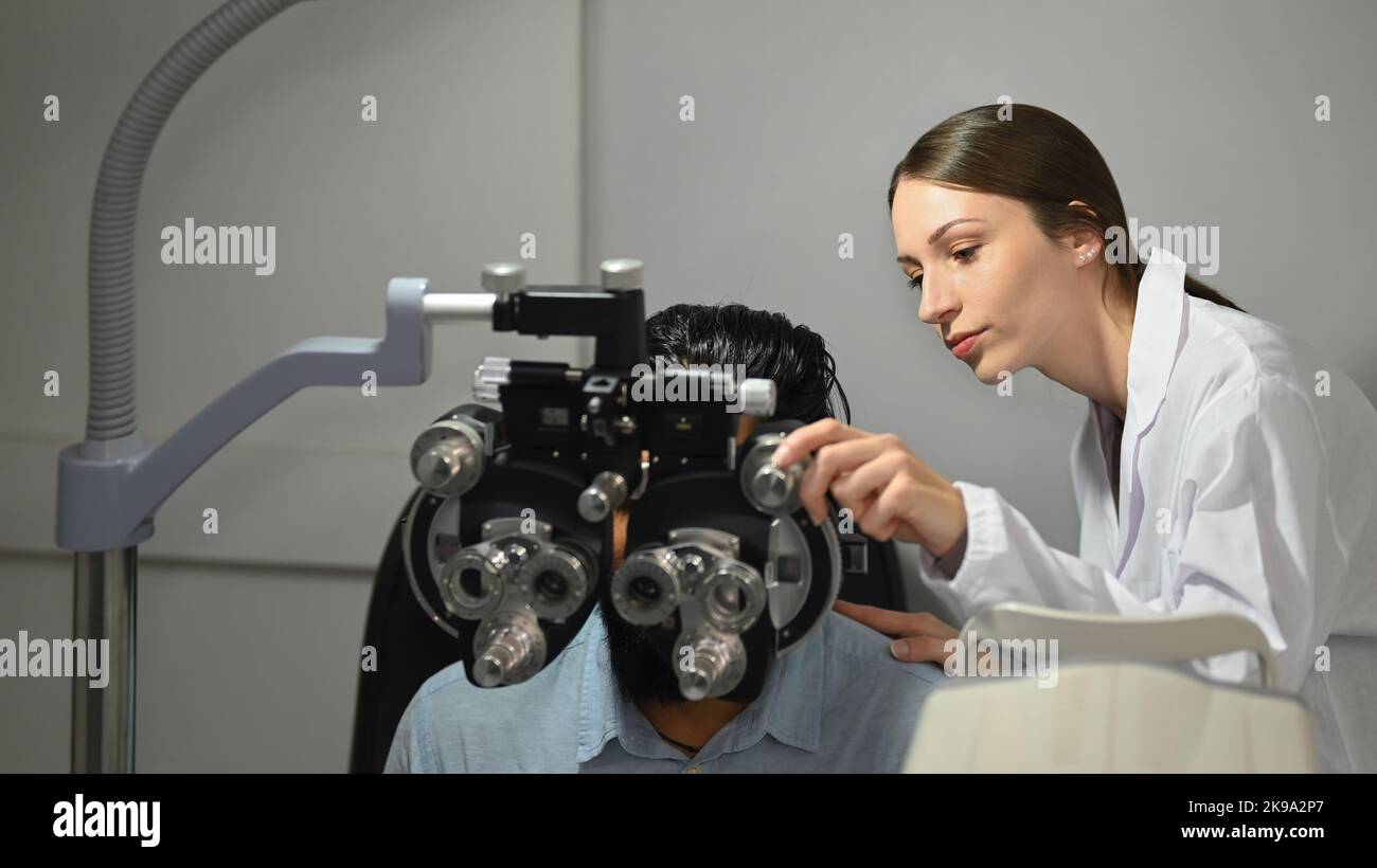 Attentive ophthalmologist checking eye vision of patient with phoropter ...