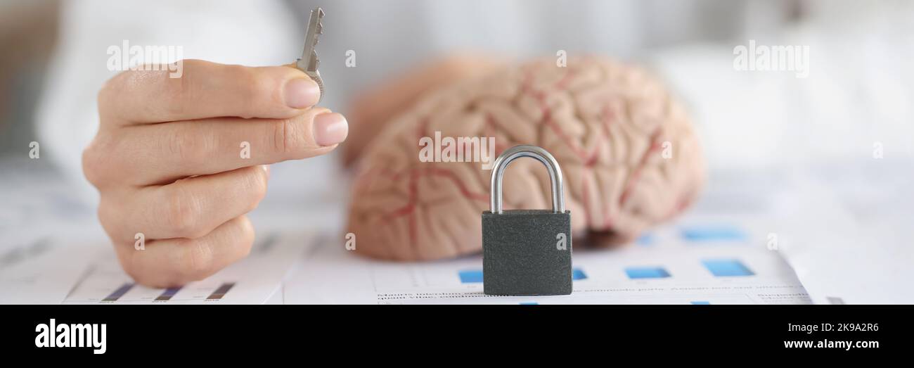 Woman hold key, lock and human brain on desk, symbol as key to someones ...