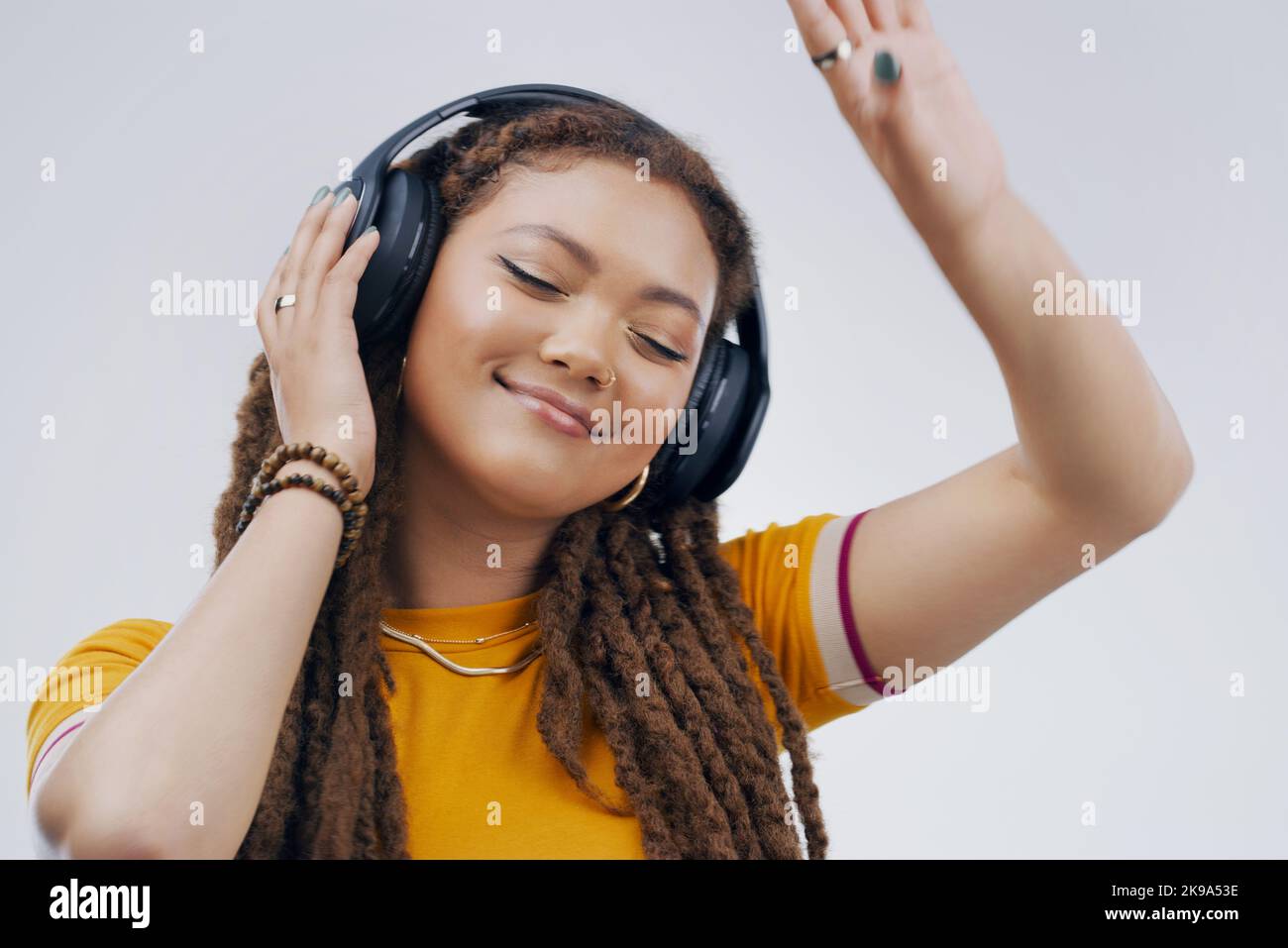 Turn it up. Studio shot of an attractive young woman dancing against a ...