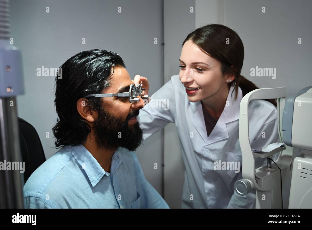 Beautiful female ophthalmologist examining eyesight of Indian male ...