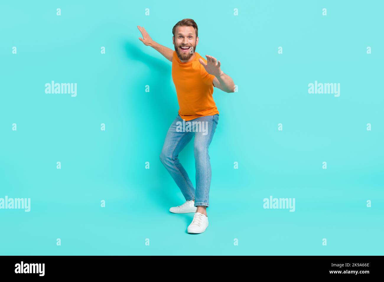 Full Length Photo Of Cheerful Ecstatic Man Muscular Beard Wear Orange T Shirt Jeans Surf On