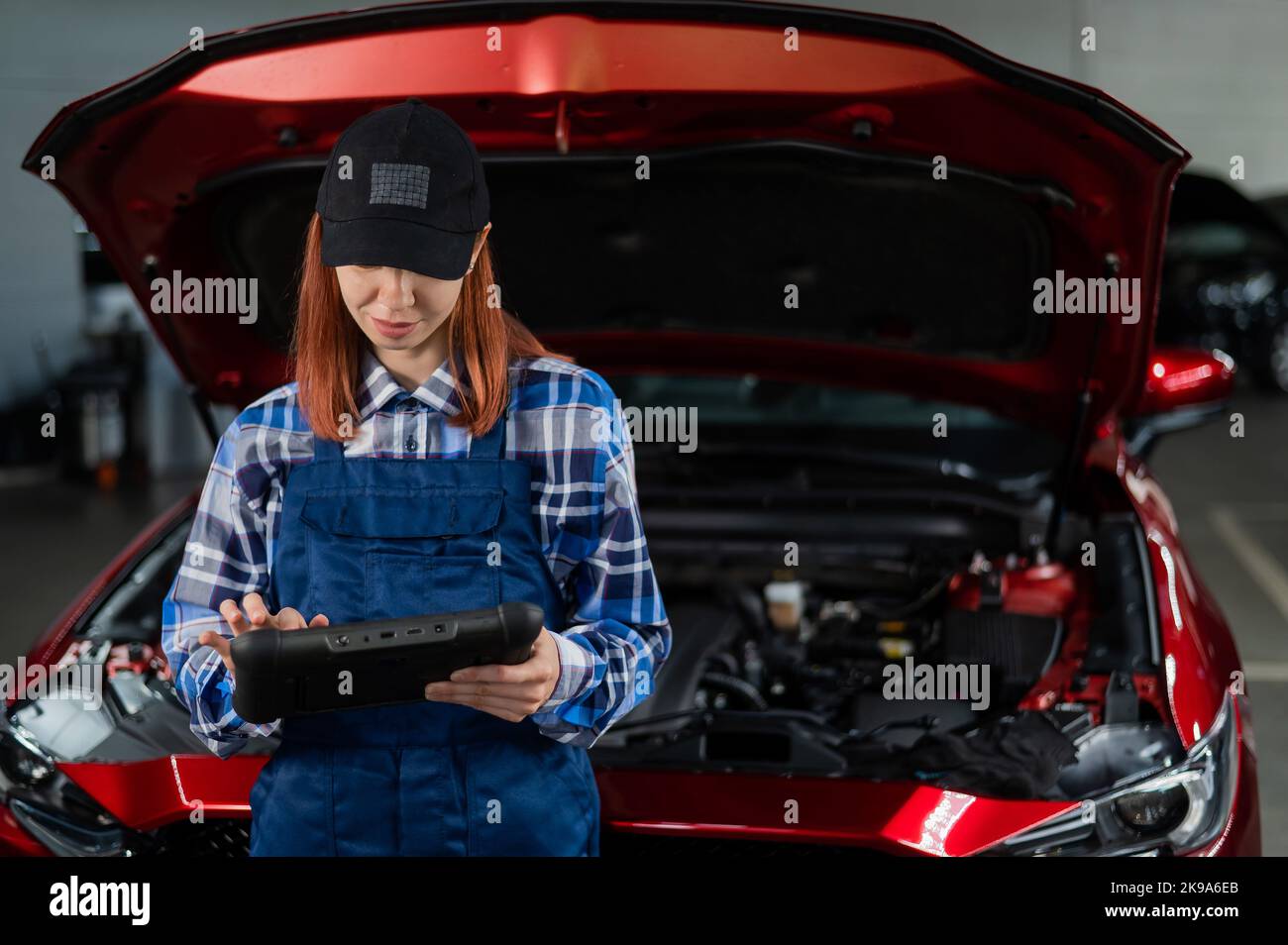 Caucasian female auto mechanic uses a special computer to diagnose ...