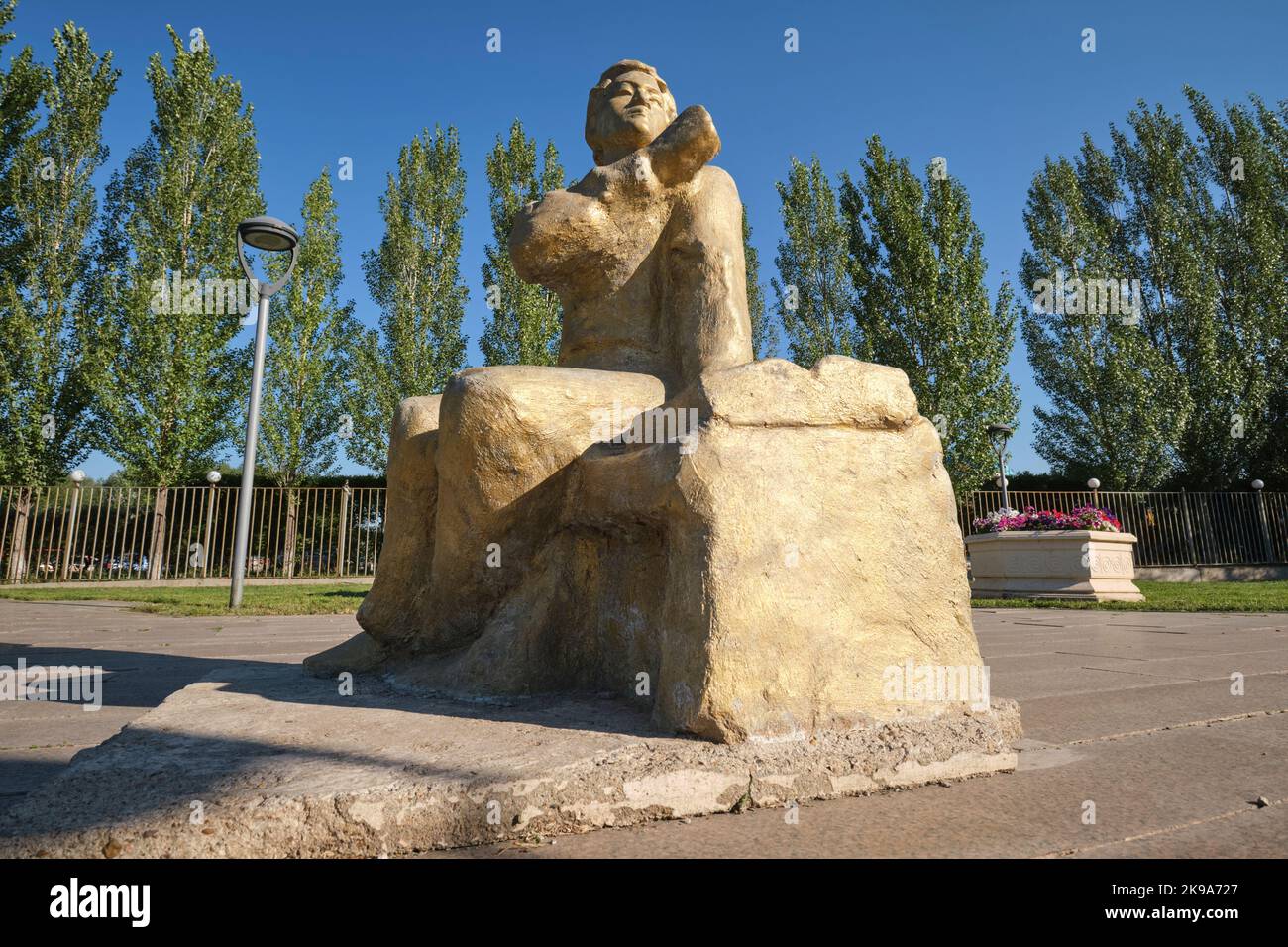 A gold painted statue, sculpture of a student, proudly sitting and ...