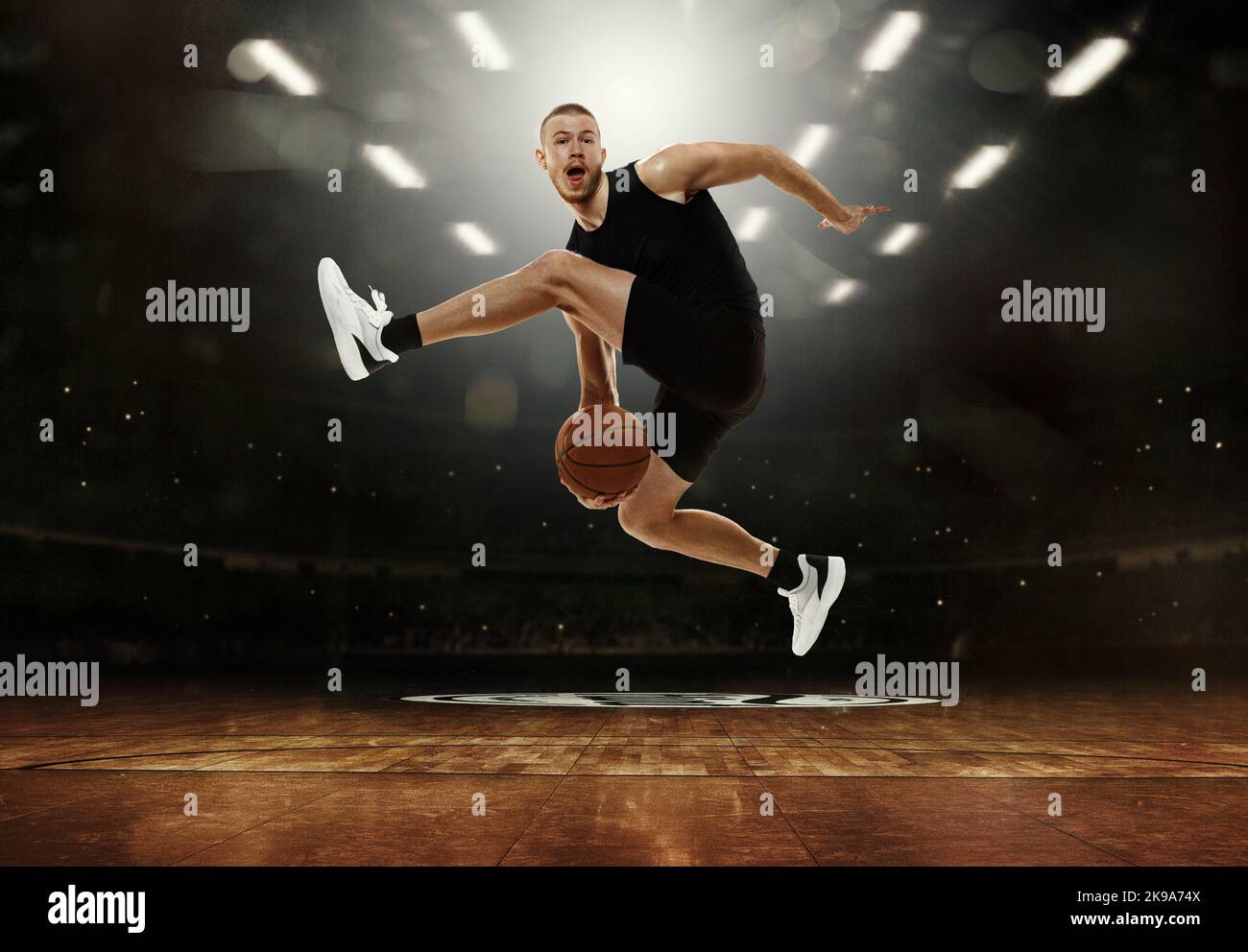 Energetic young professional basketball player jumping with ball at ...