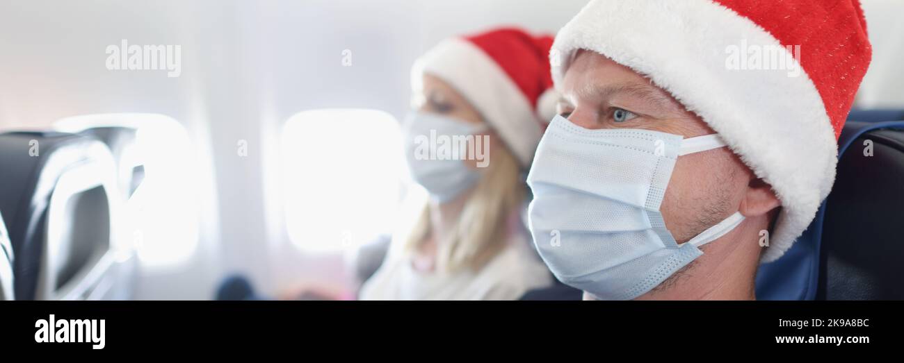 Man and woman in santa hats and protective face masks flying in ...