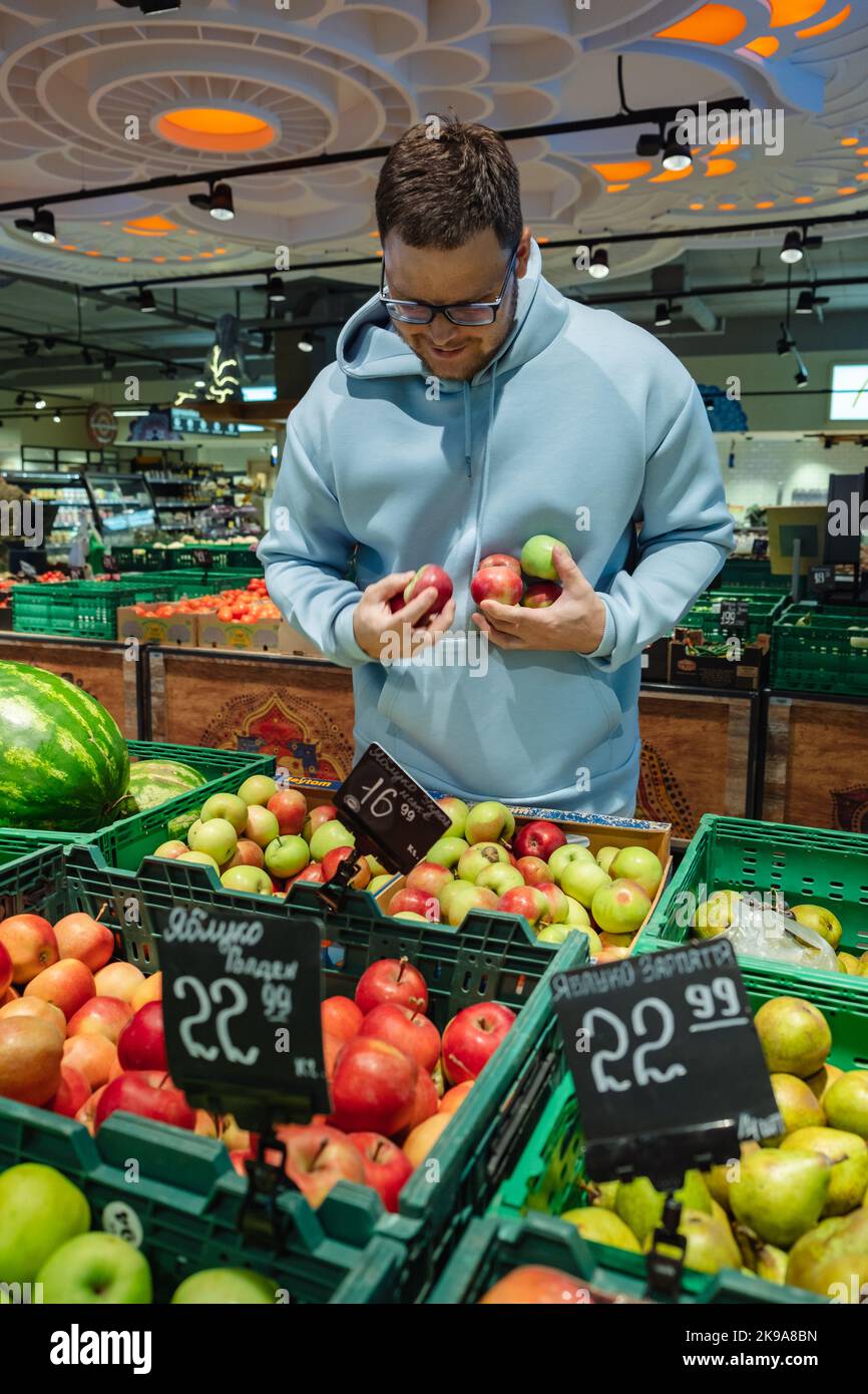 A man buys food, . A male customer chooses apples, taking products from ...