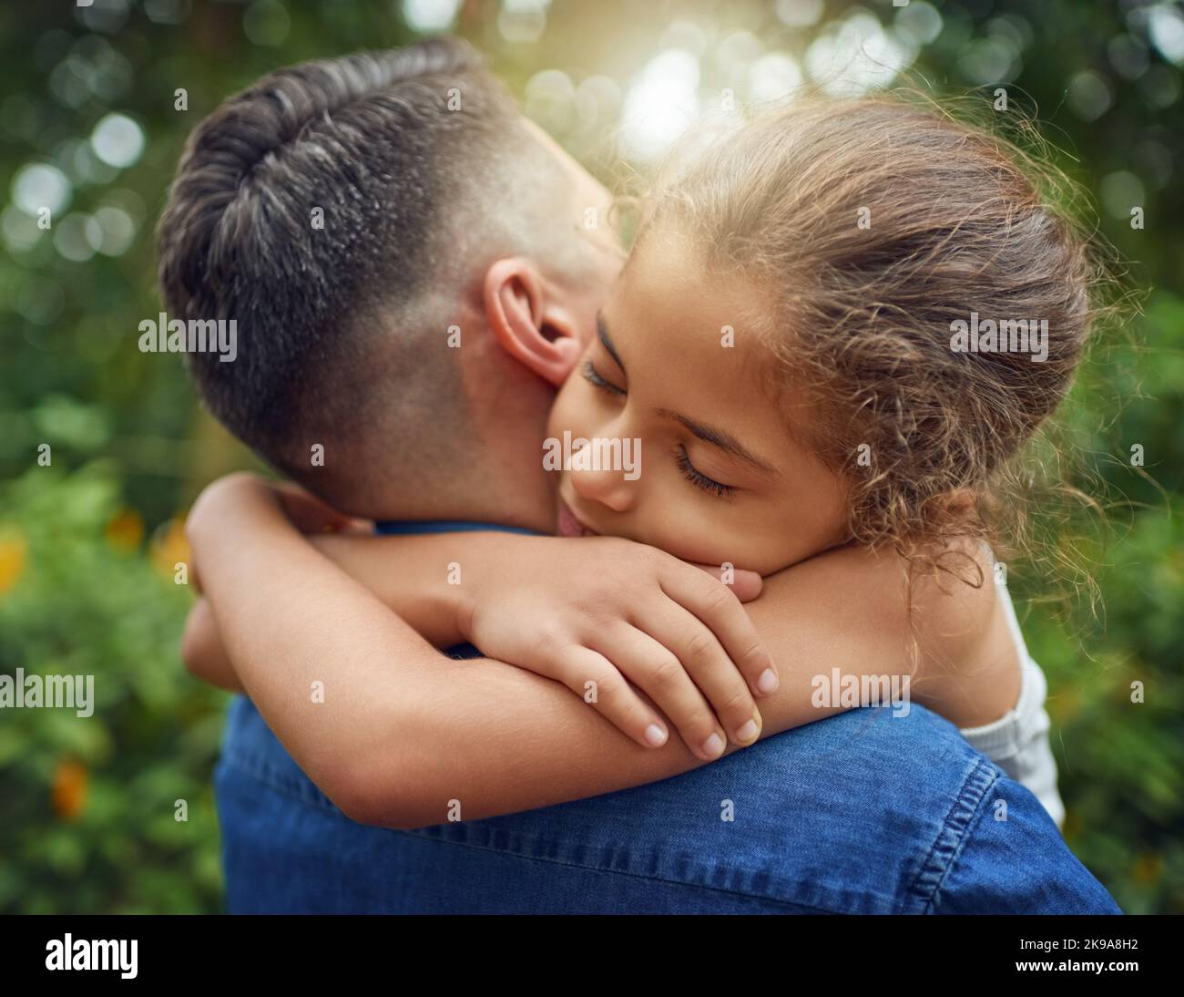 Safety in daddys arms. an affectionate father embracing his daughter at ...
