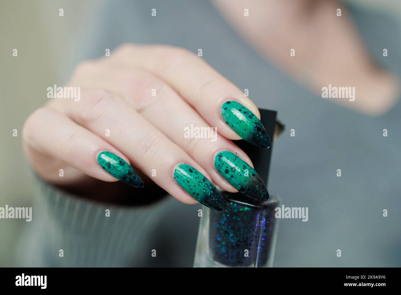Female hand with long nails and green-black thermo french nail polish ...