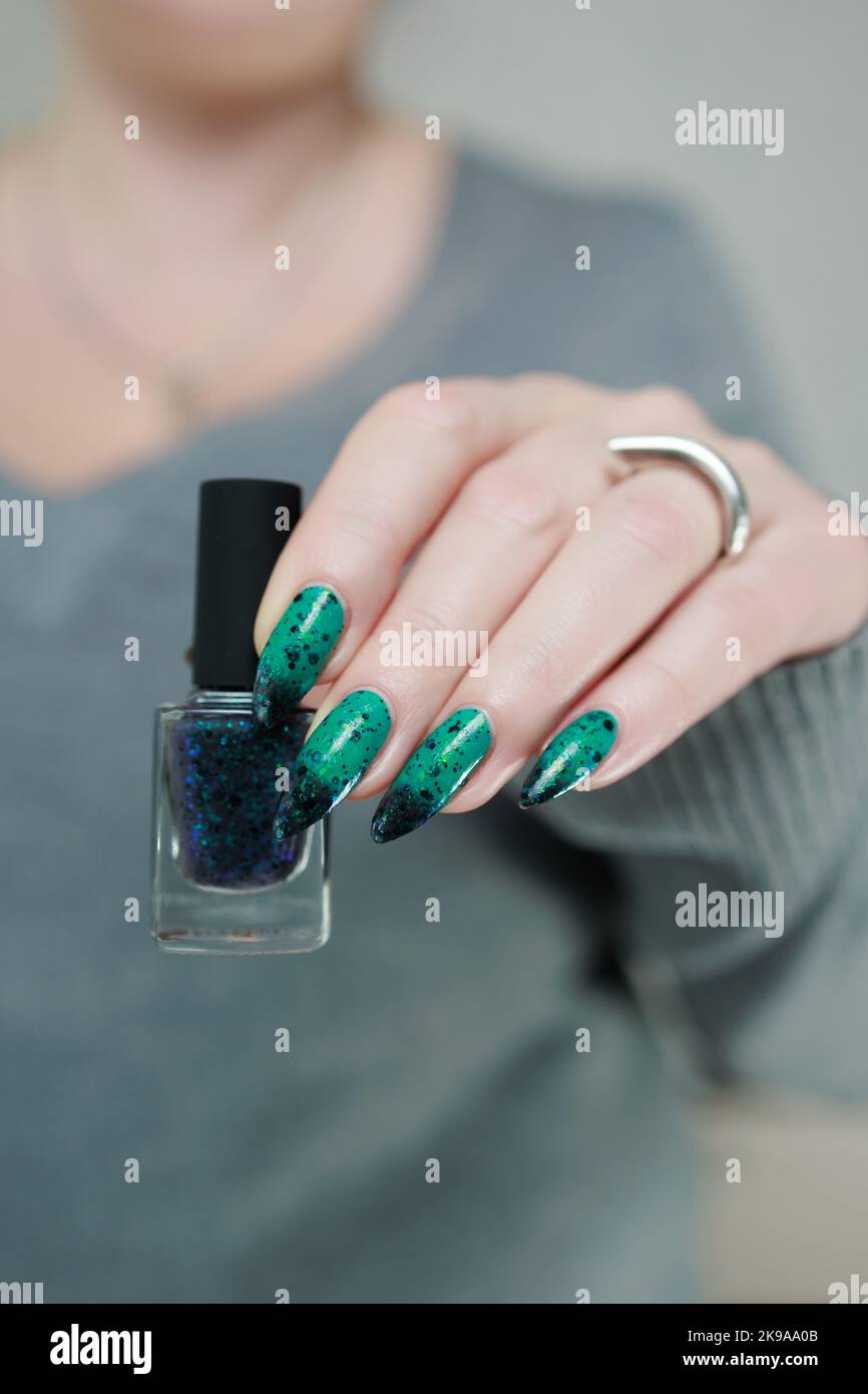 Female hand with long nails and green-black thermo french nail polish ...